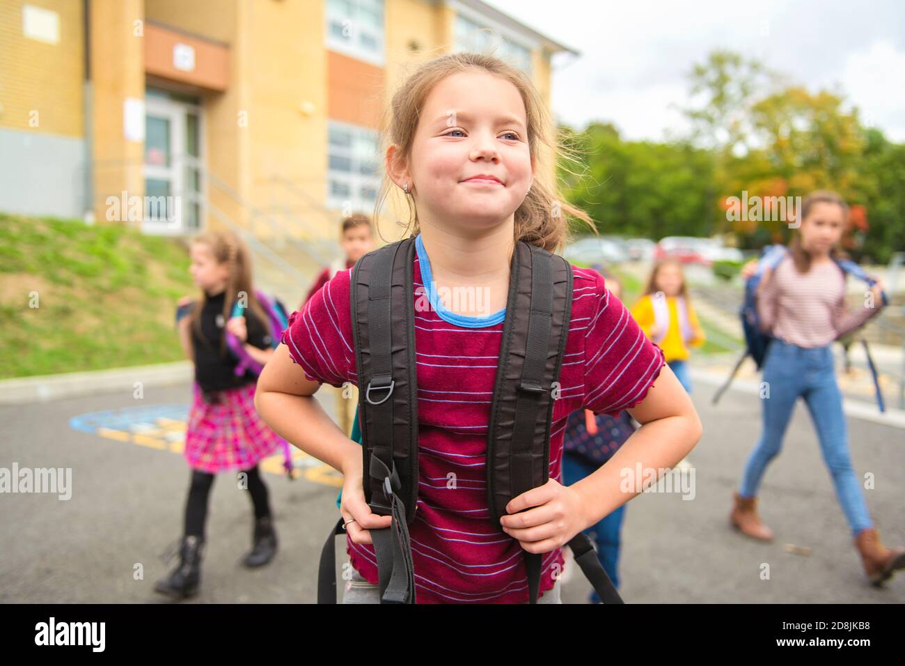 A schoolgirl walking with other student on the back Stock Photo - Alamy
