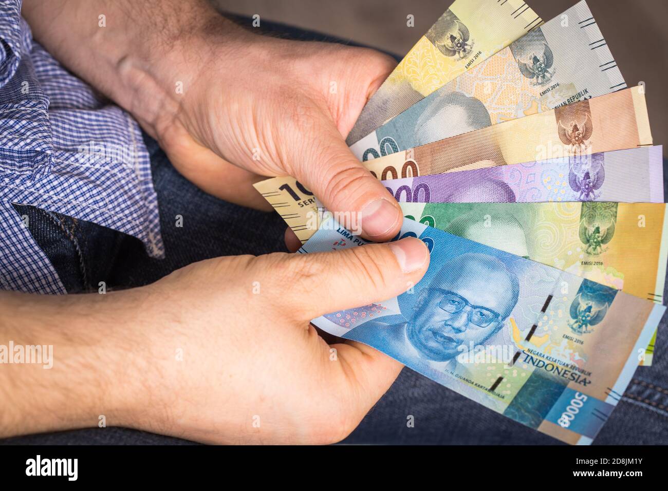 a man holding a bundle of Indonesian rupees in his hands. Money of any ...