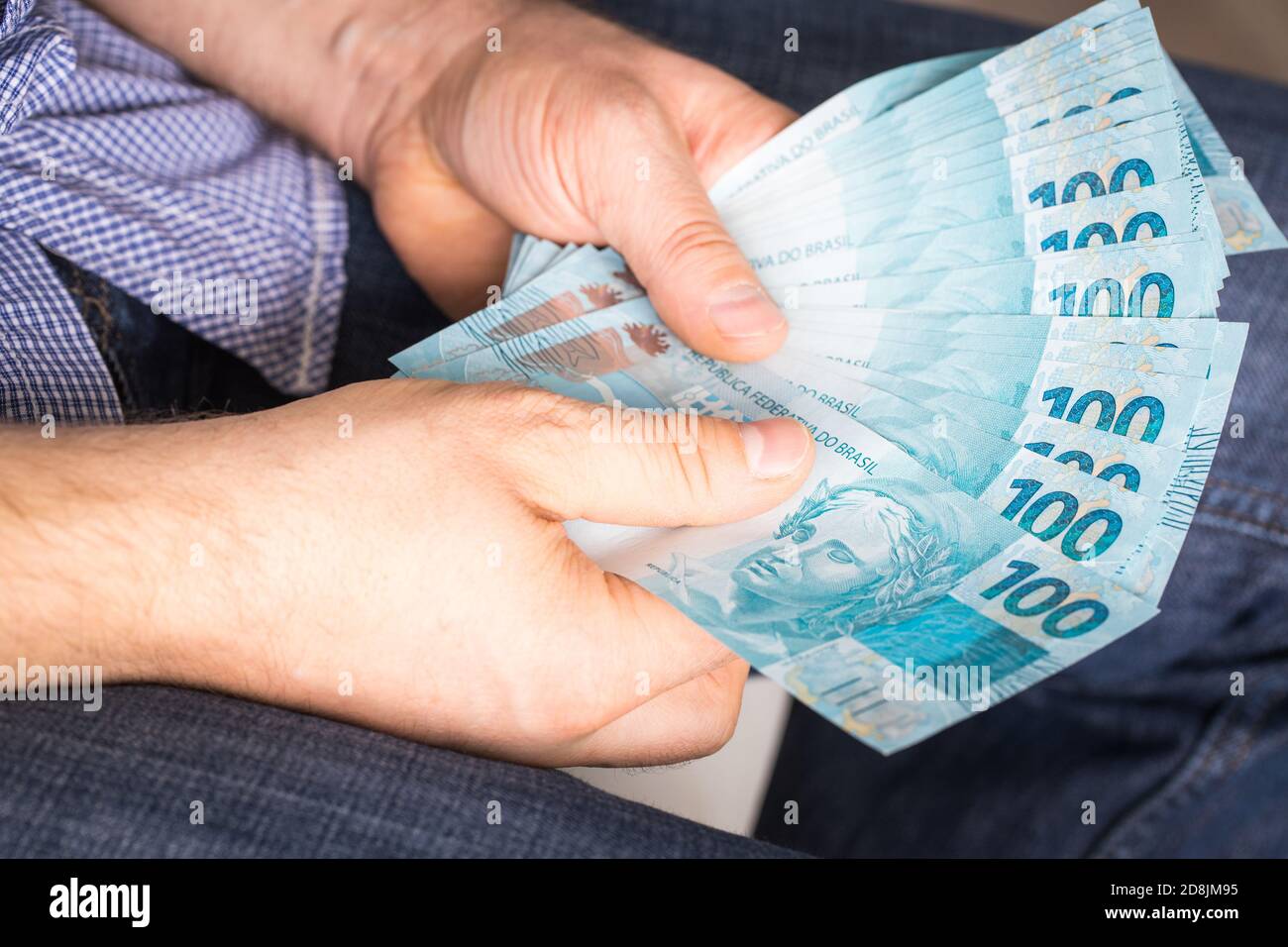 a man holding in his hand a bundle of high-value Brazilian money Stock ...