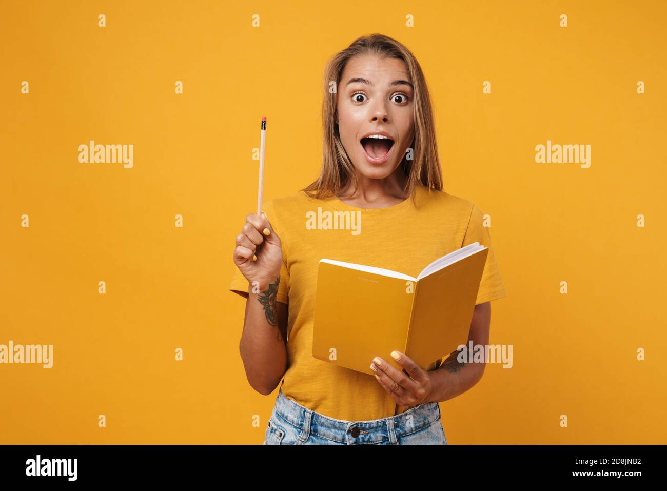 Image of young surprised woman holding exercise book isolated over ...