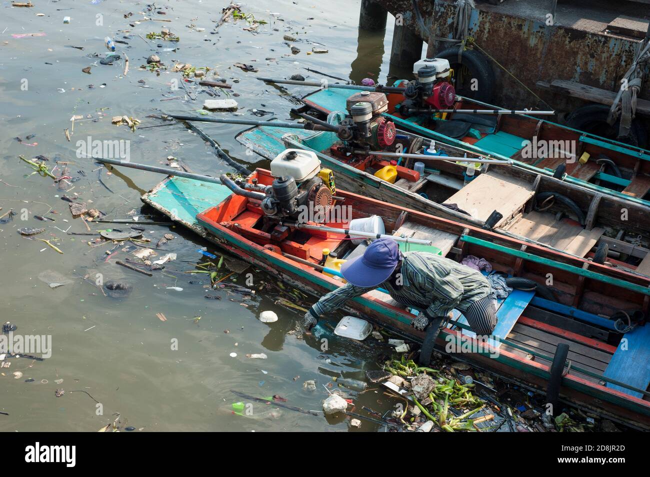 Taxi boats on Chao Phraya river in Bangkok, Thailand. A woman picks the ...