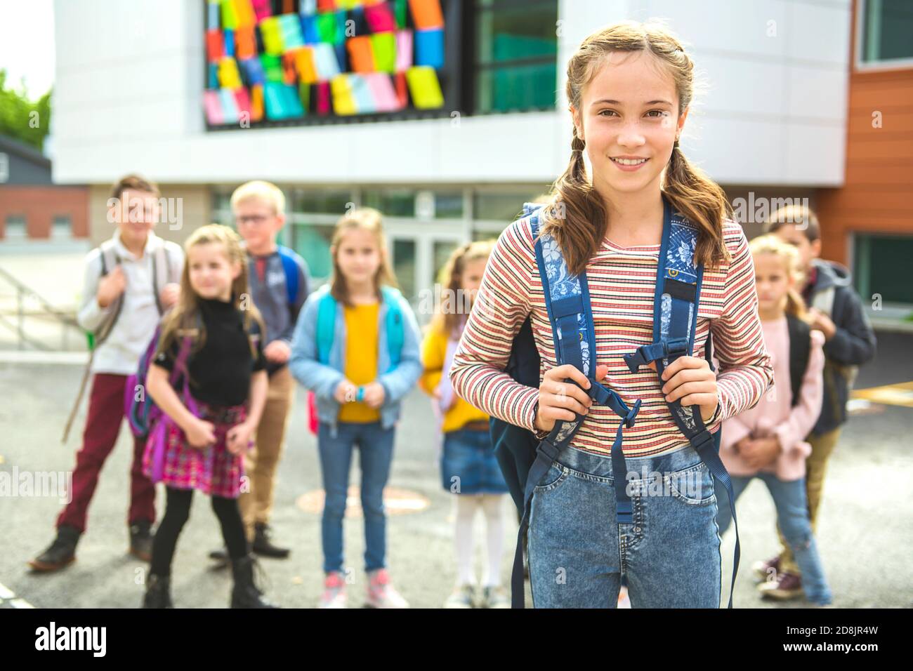 A schoolgirl standing with other student on the back Stock Photo - Alamy