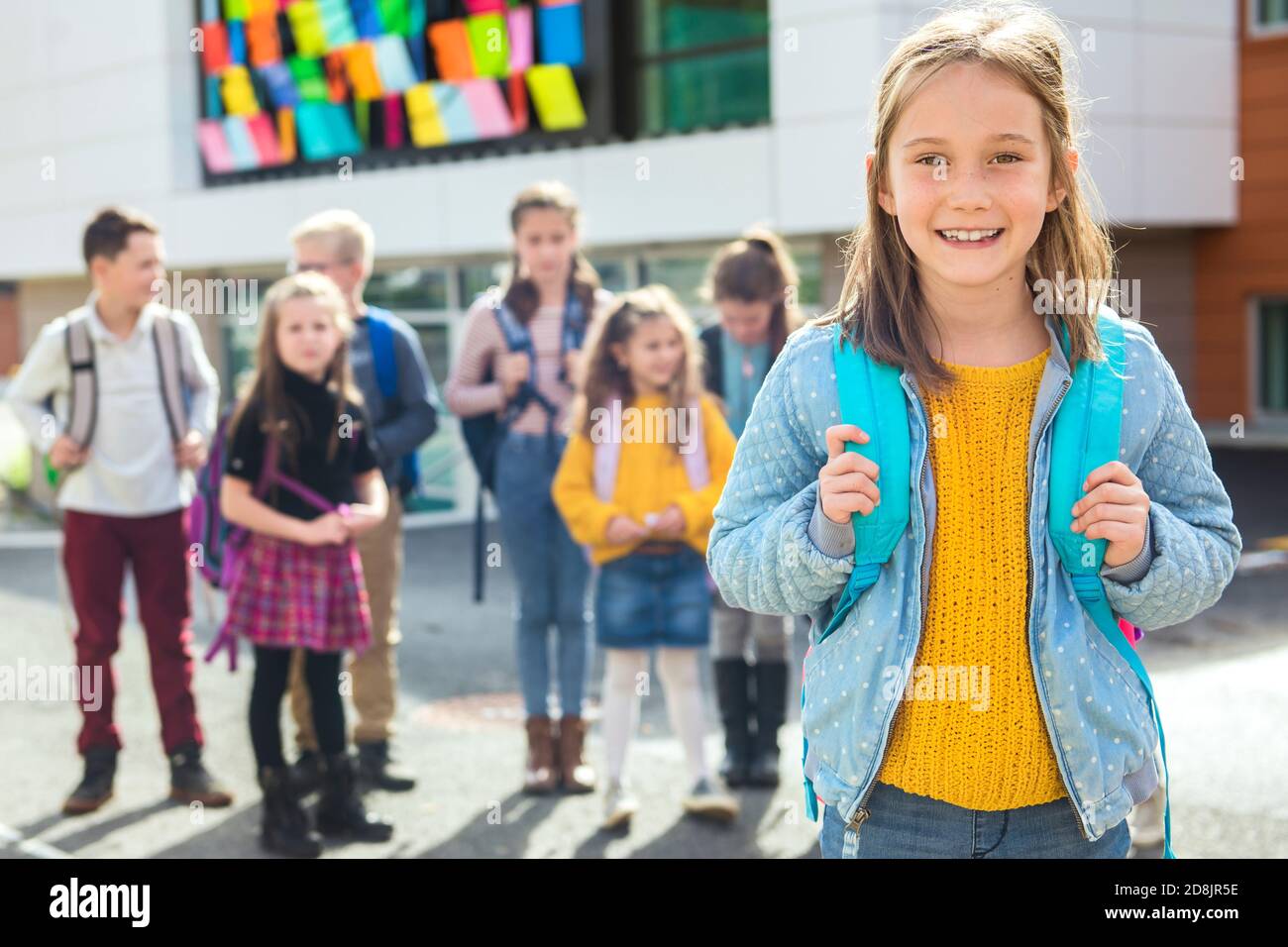 A schoolgirl standing with other student on the back Stock Photo - Alamy