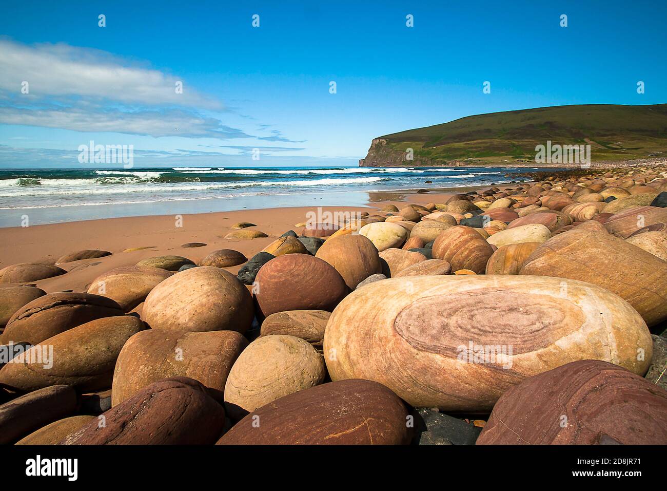 Big round stones with pattern on sandy scottish beach with sea and ...