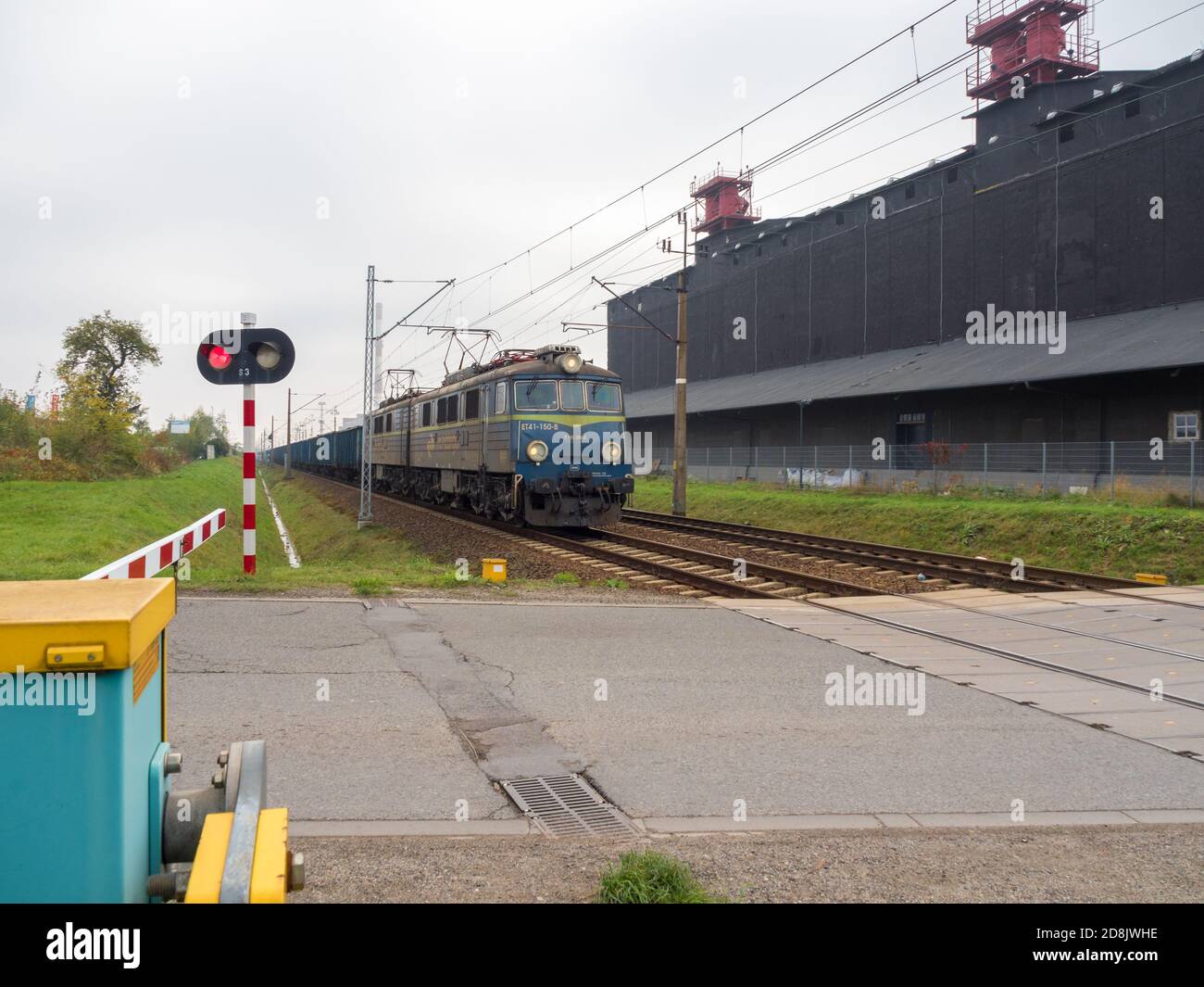 View of a railroad crossing when a freight train passes Stock Photo - Alamy