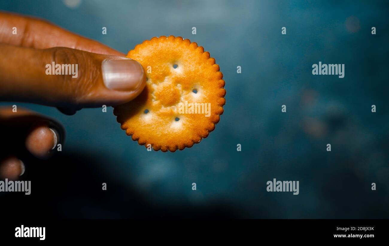 Male hand holding a Cracker in his hand on a blurred background Stock ...
