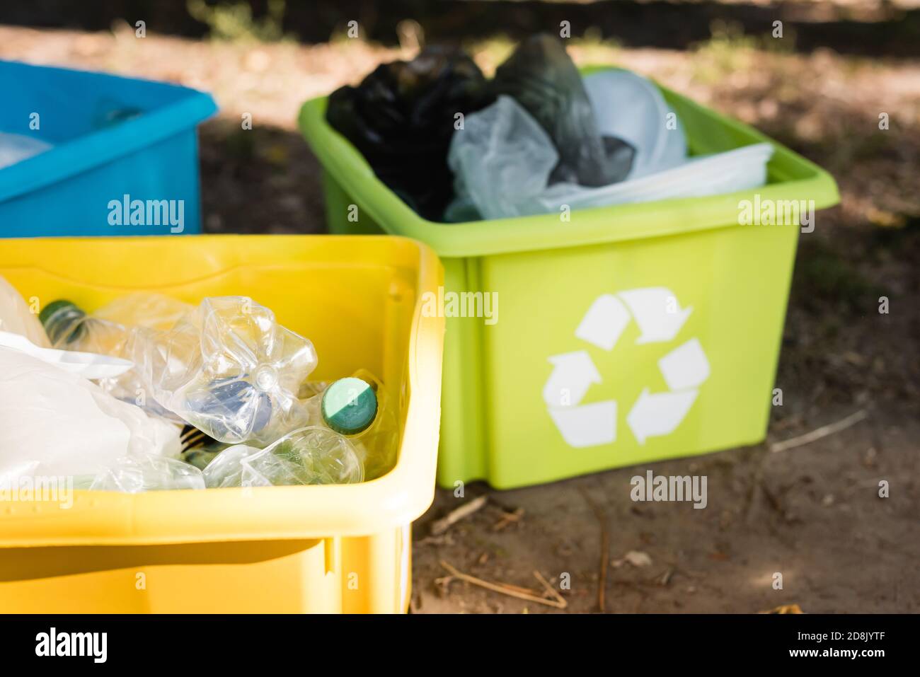 containers with recycling emblems, full of plastic waste on blurred ...