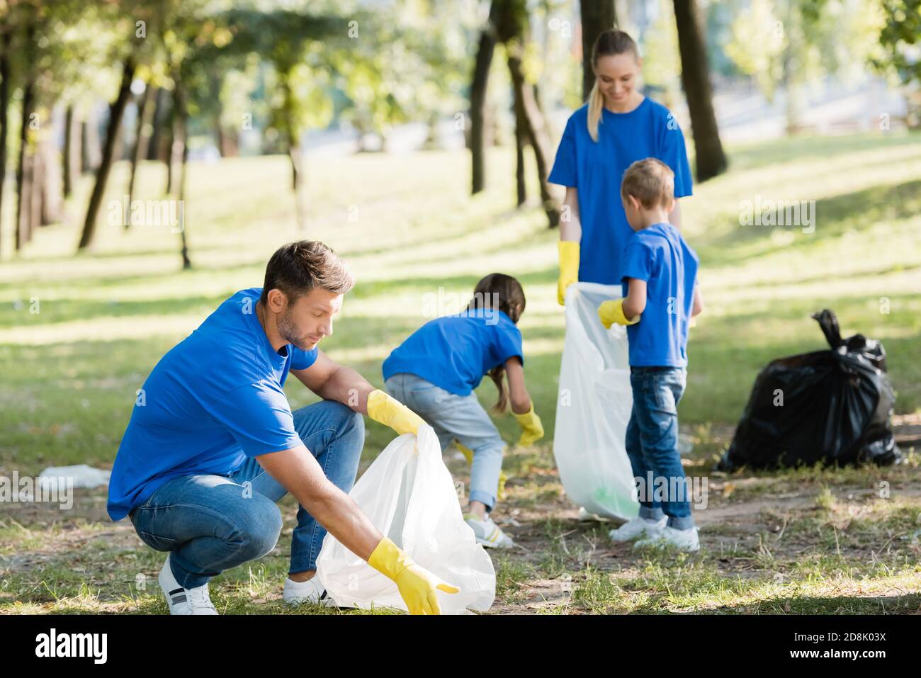 man collecting waste in recycled bag near family on blurred background ...