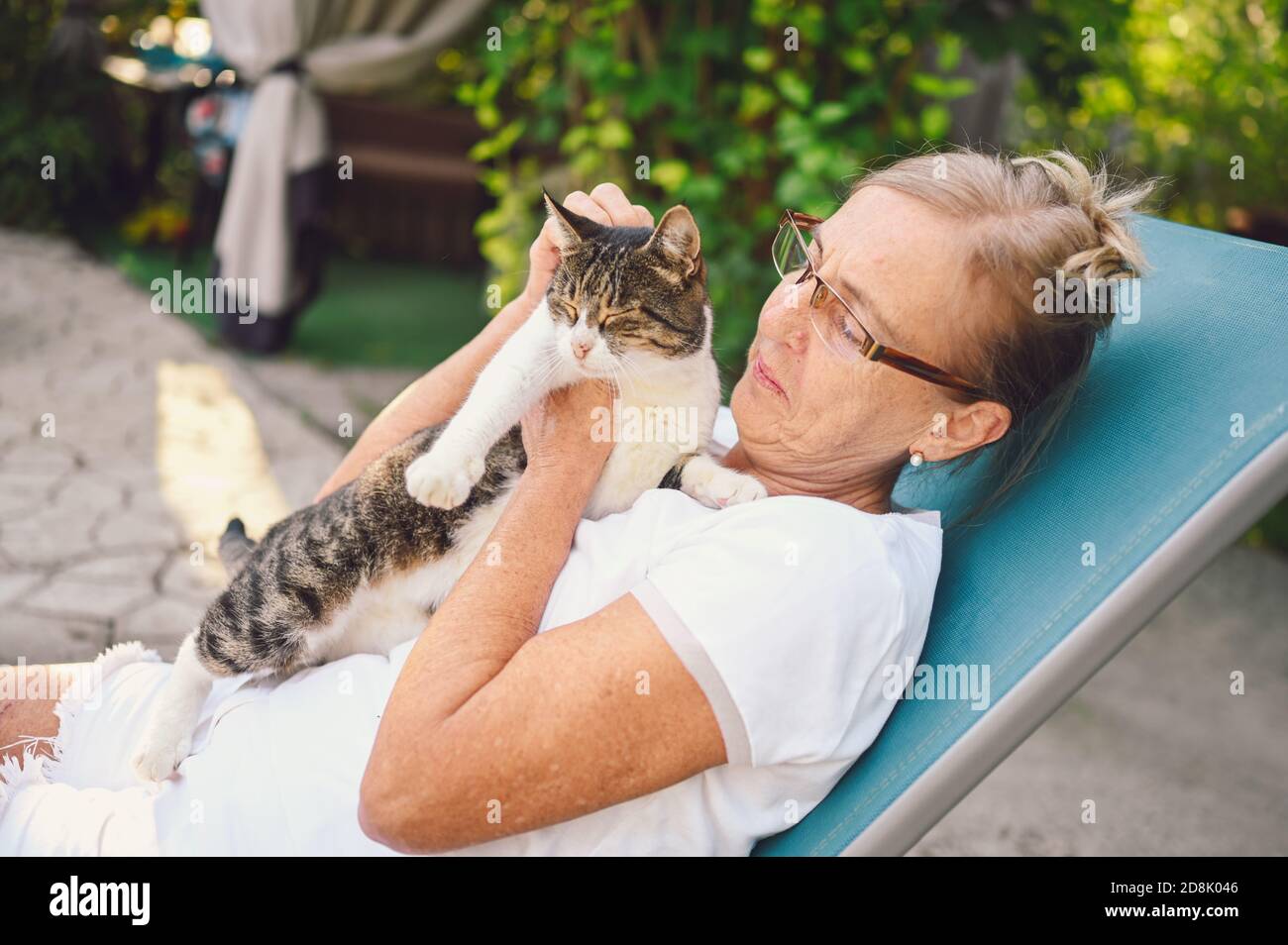 Happy smiling senior elderly woman in glasses relaxing in summer garden ...