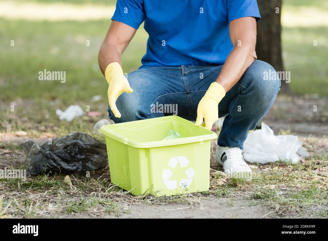 partial view of man collecting plastic waste in container with ...