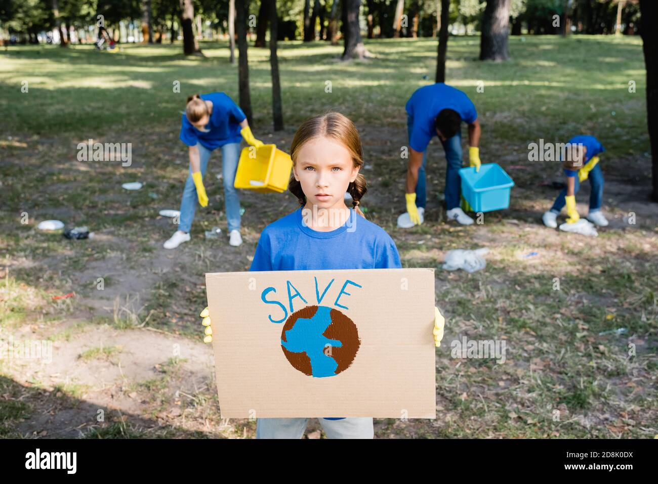 girl holding placard with globe and save inscription, while family ...