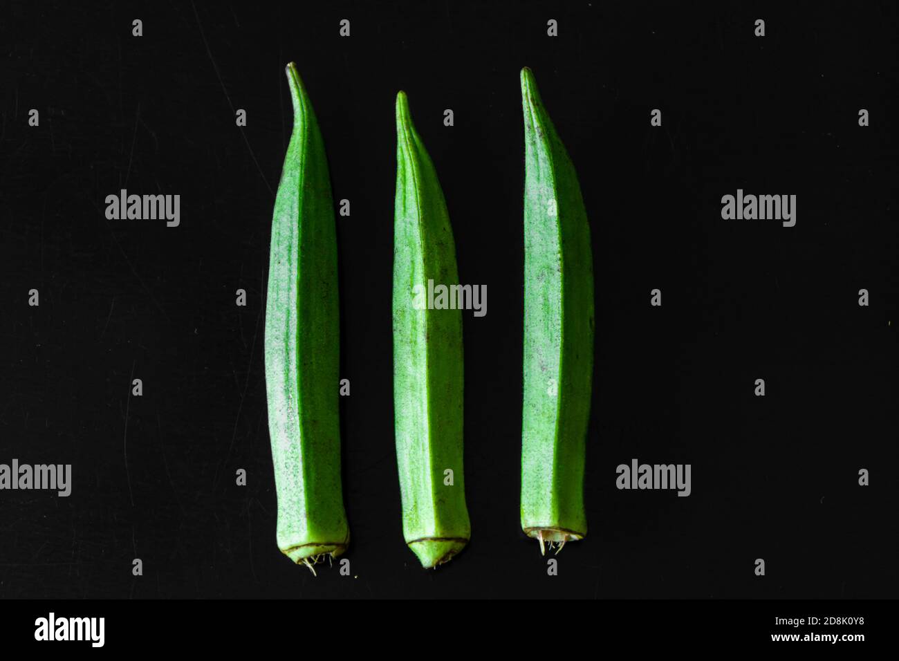 Green tropical vegetable called ladies' fingers or ochro on black ...