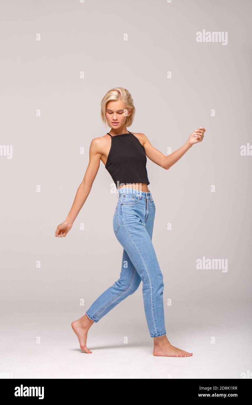 Freestyle. Young blonde woman in jeans and top making step concentrated ...