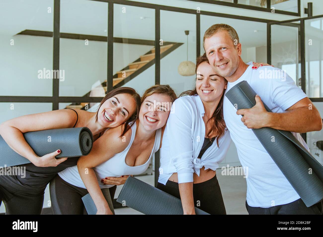 Smiling young people having fun after yoga class indoor. Group of happy ...