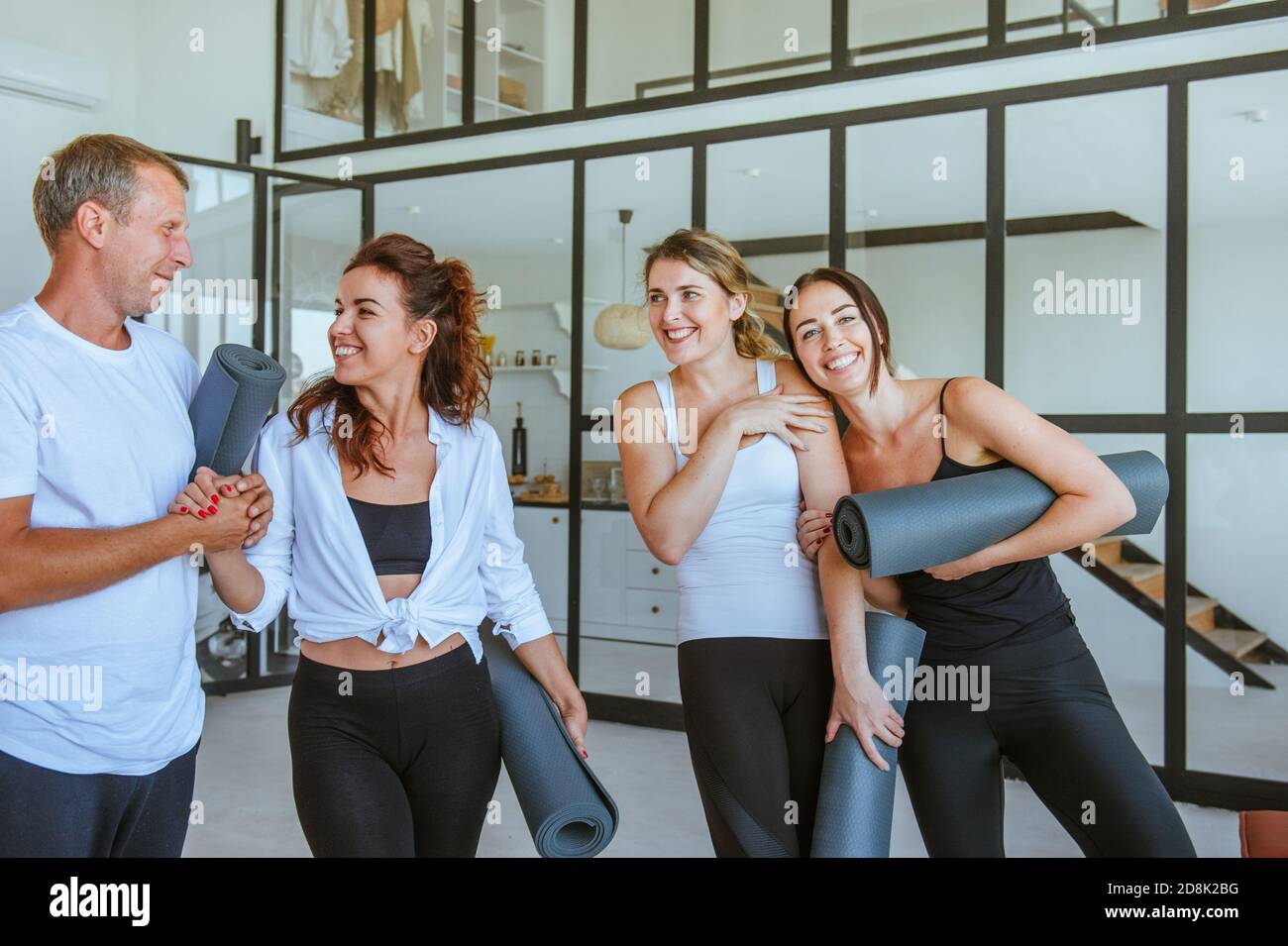 Smiling young people having fun after yoga class indoor. Group of happy ...