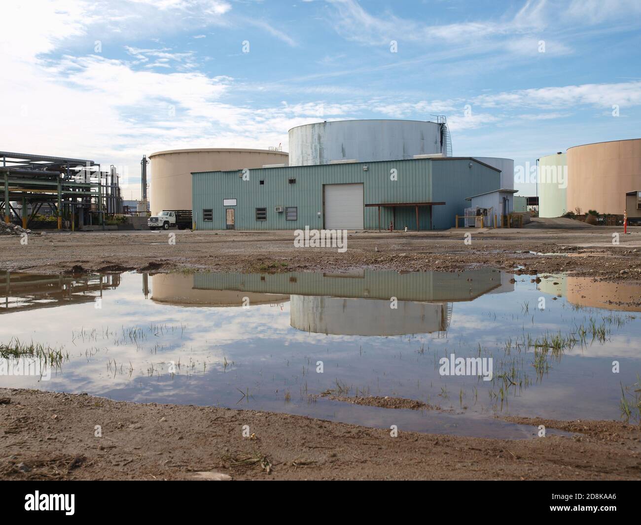 Reflection of small metal industrial building and fuel storage tanks in ...