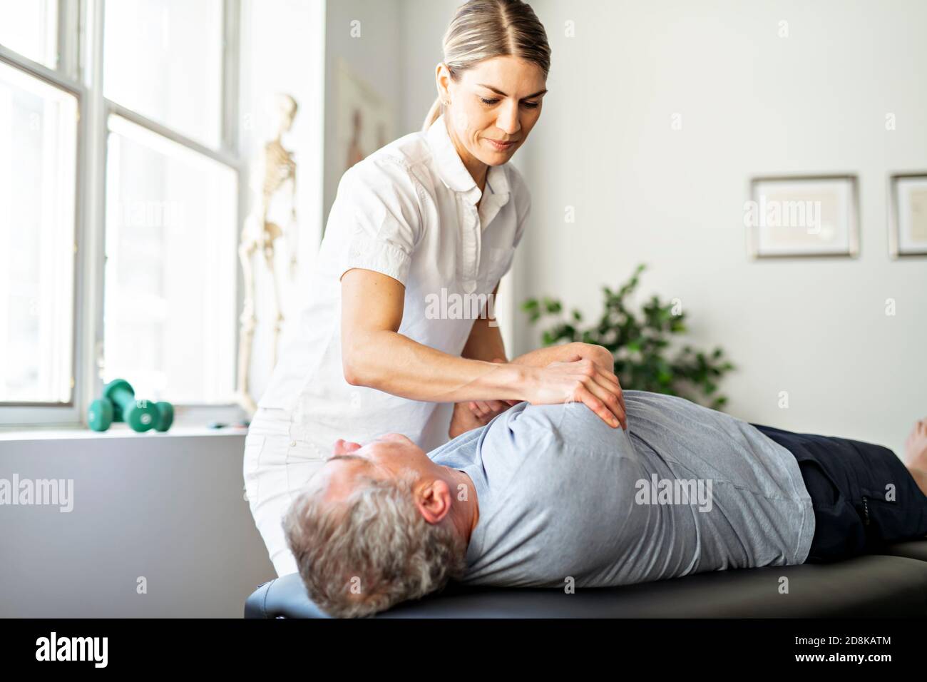 A Modern rehabilitation physiotherapy worker with senior client Stock ...