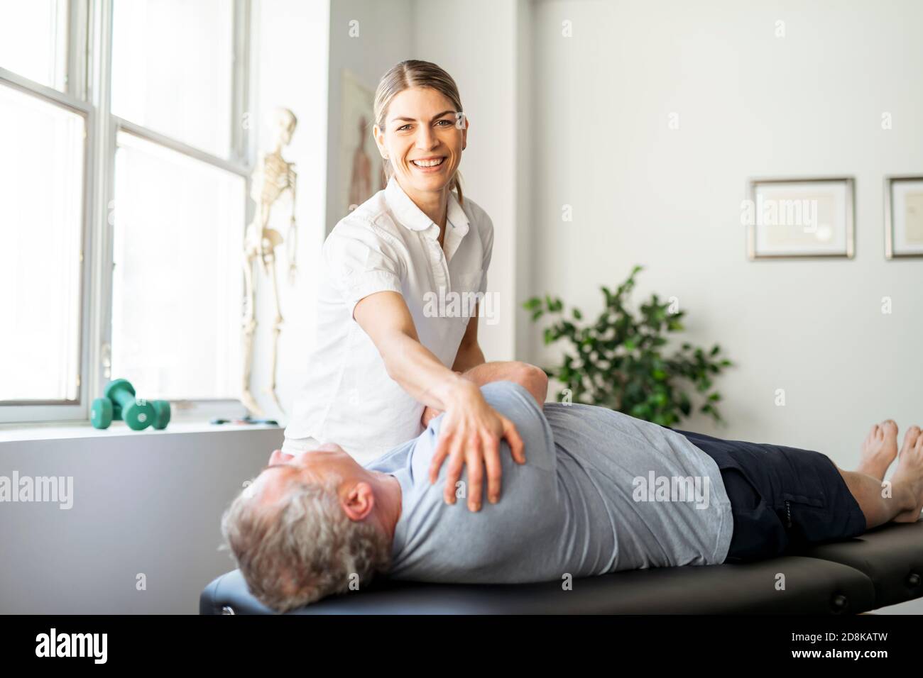 A Modern rehabilitation physiotherapy worker with senior client Stock ...