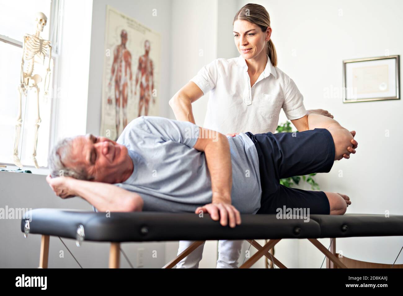 A Modern rehabilitation physiotherapy worker with senior client Stock ...
