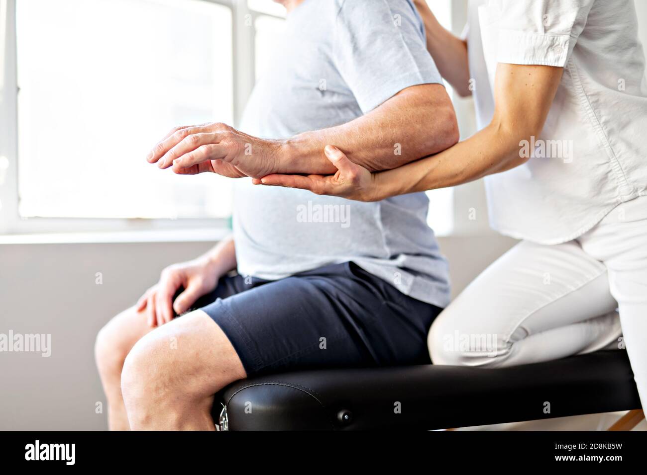 A Modern rehabilitation physiotherapy worker with senior client Stock ...