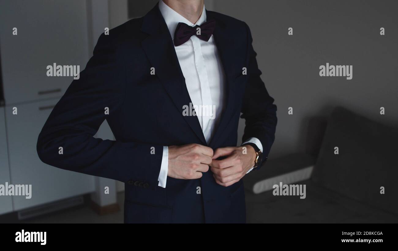 Unrecognizable man in elegant suit with neck bow closing the button ...