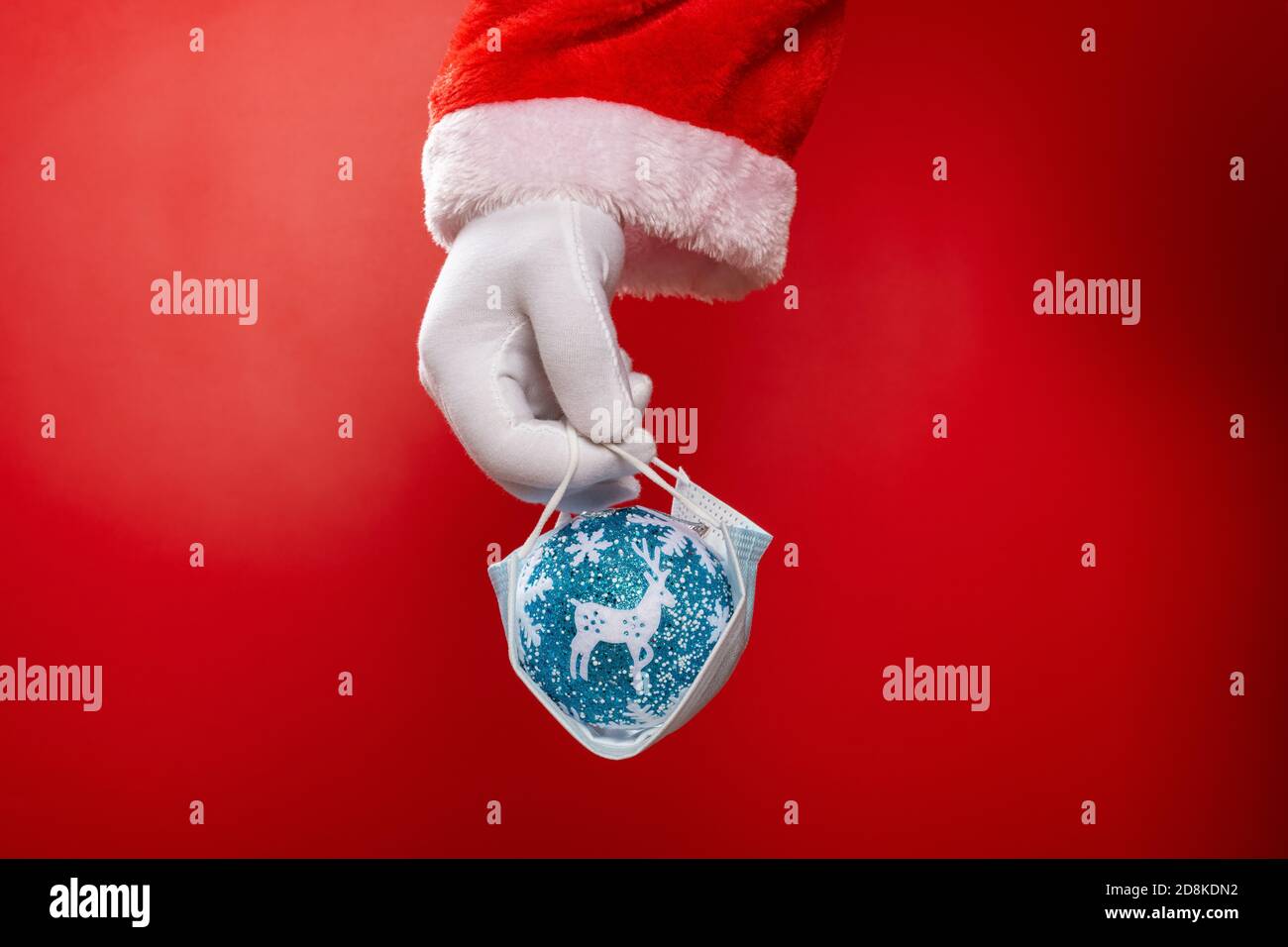 Santa Claus holding a medical mask with a blue Christmas ball on red ...