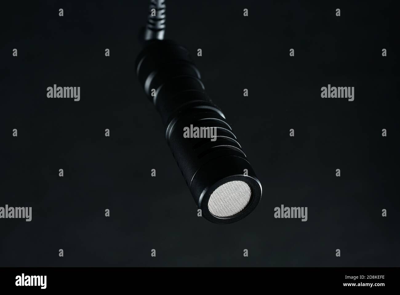 Black microphone hanging from the ceiling isolated on a black ...