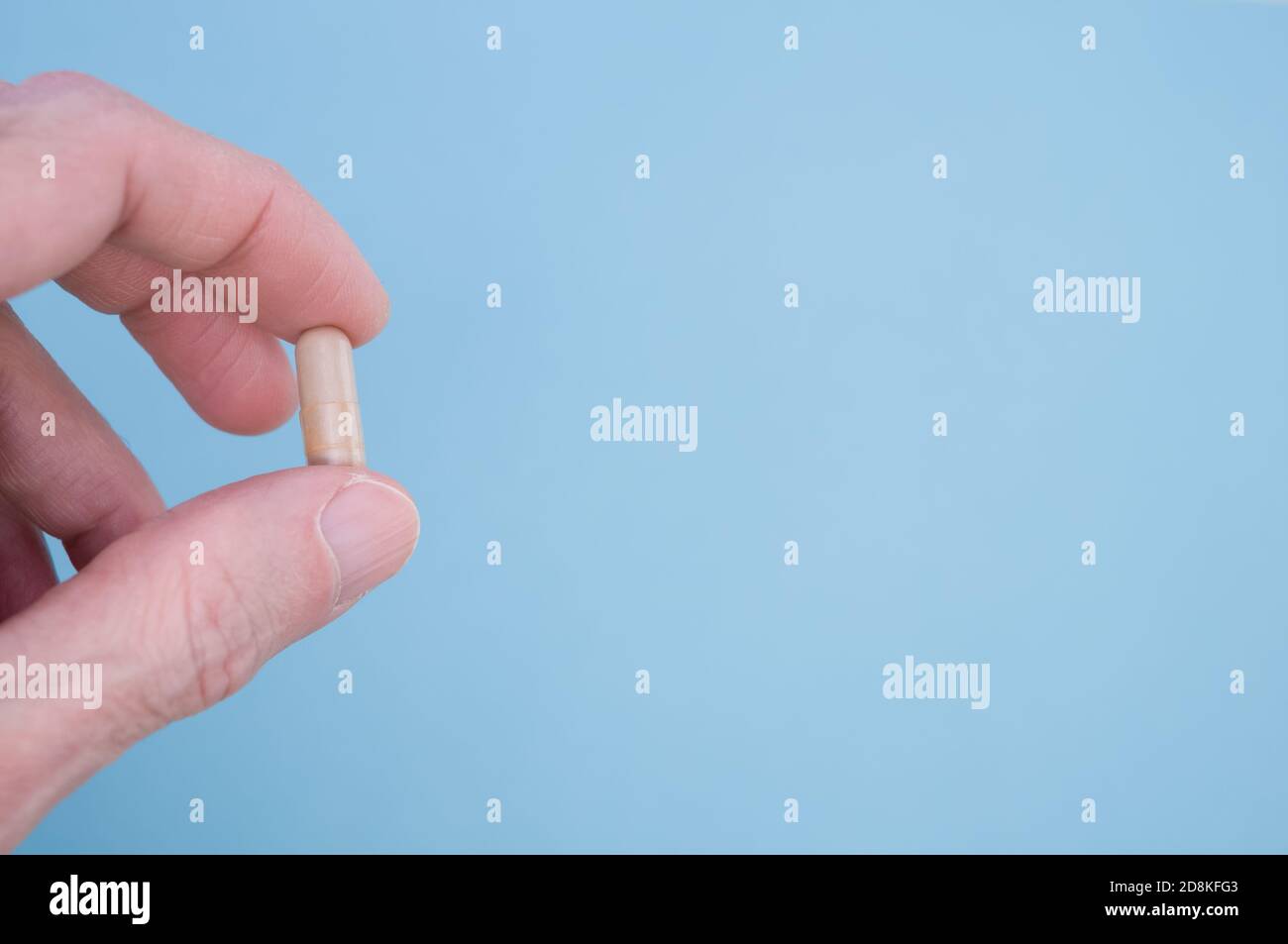 Hand holding a capsule on blue background with a copy space Stock Photo ...