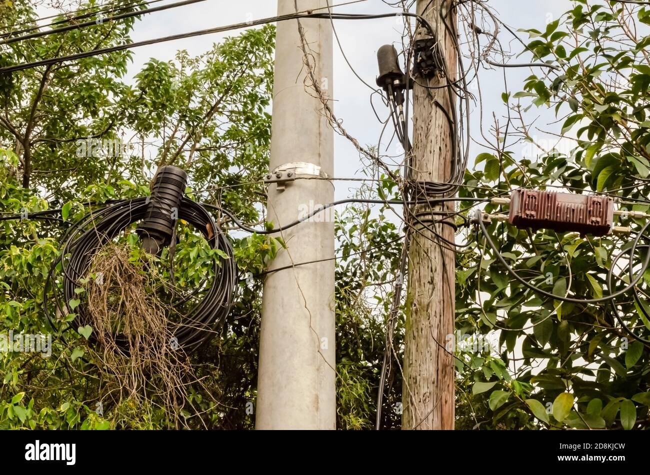 Two posts, one wooden, and the other concrete supports mulitple cables ...