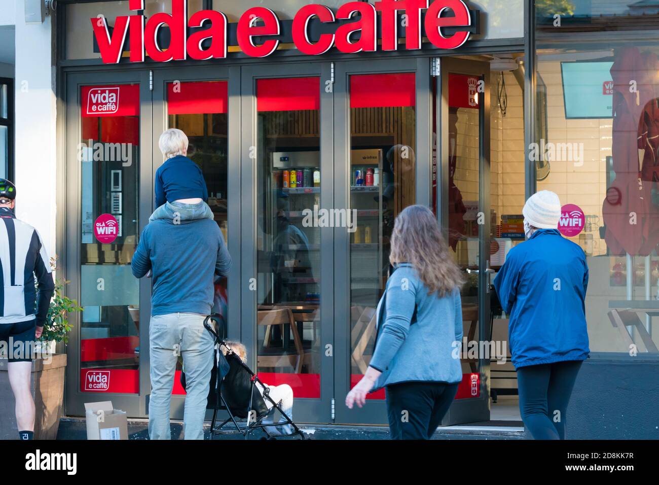 early morning customers wait outside a closed coffee shop during ...
