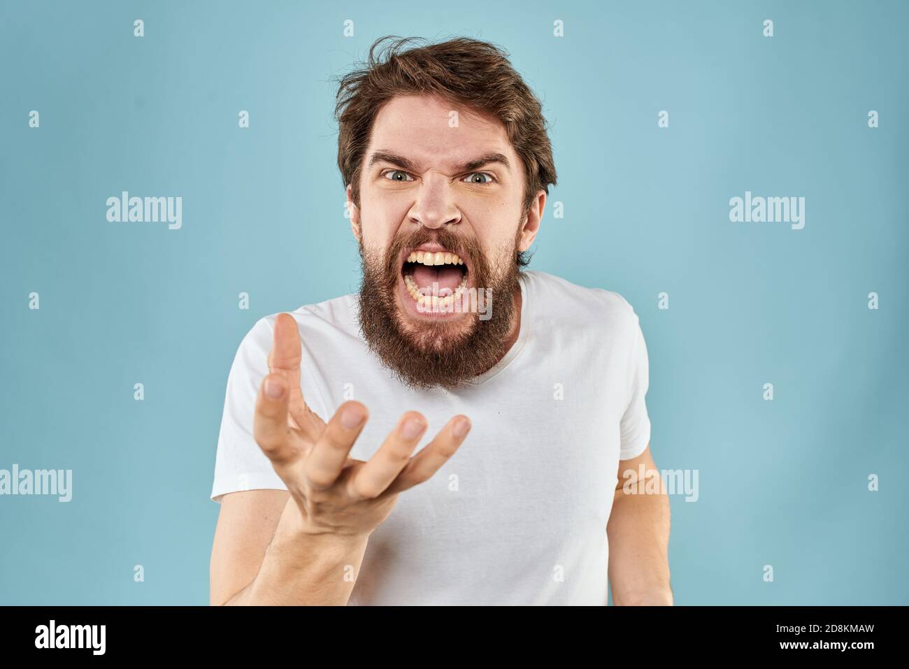 Bearded man in white T-shirt emotions gestures with hands displeased ...