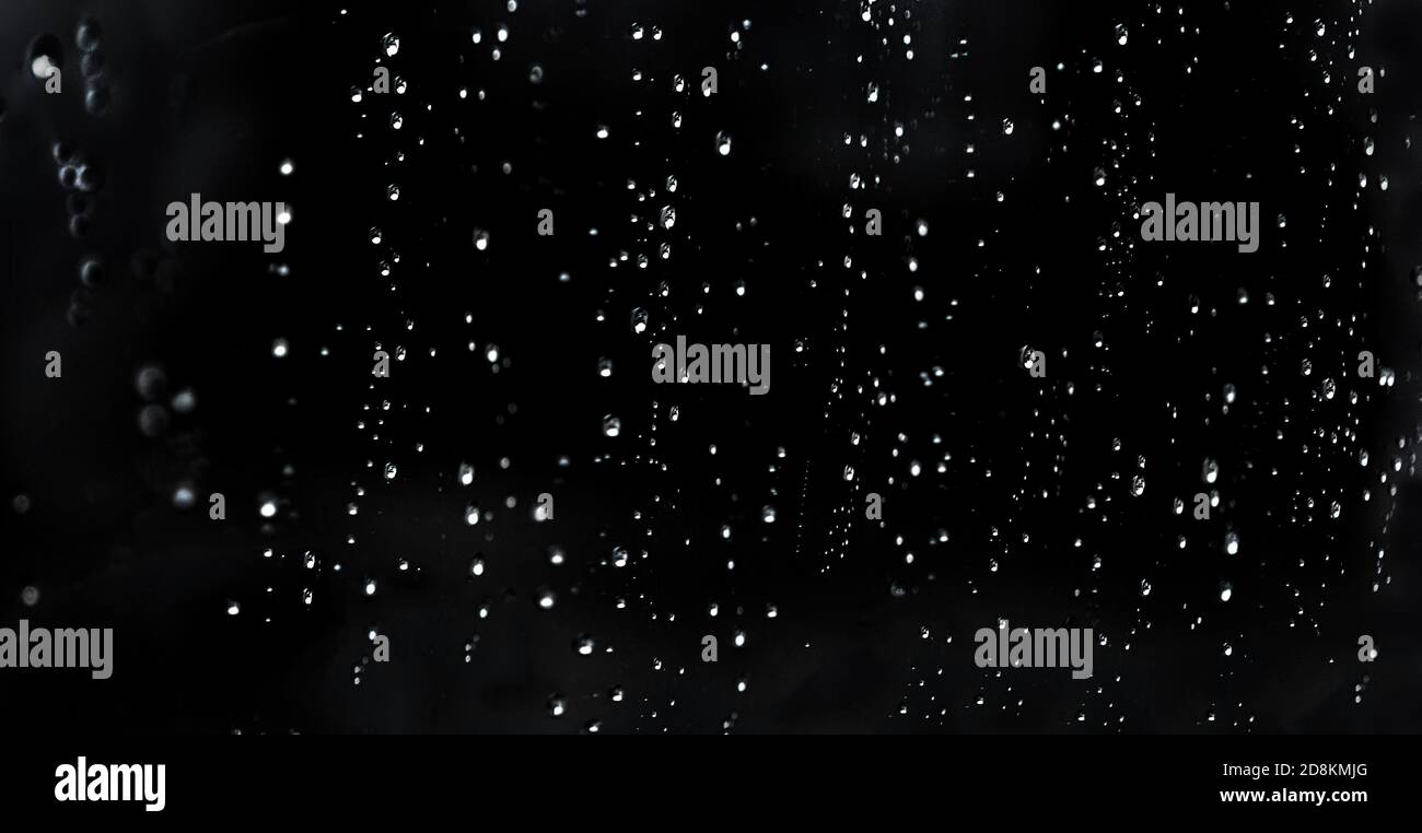 Falling Rain water drops on a black dramatic window glass. Autumn ...