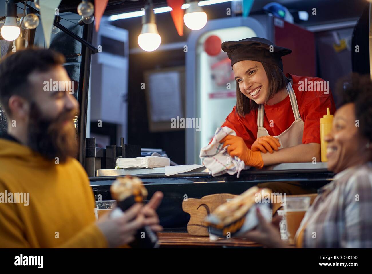 friends socializing with employee in fast food service, eating ...