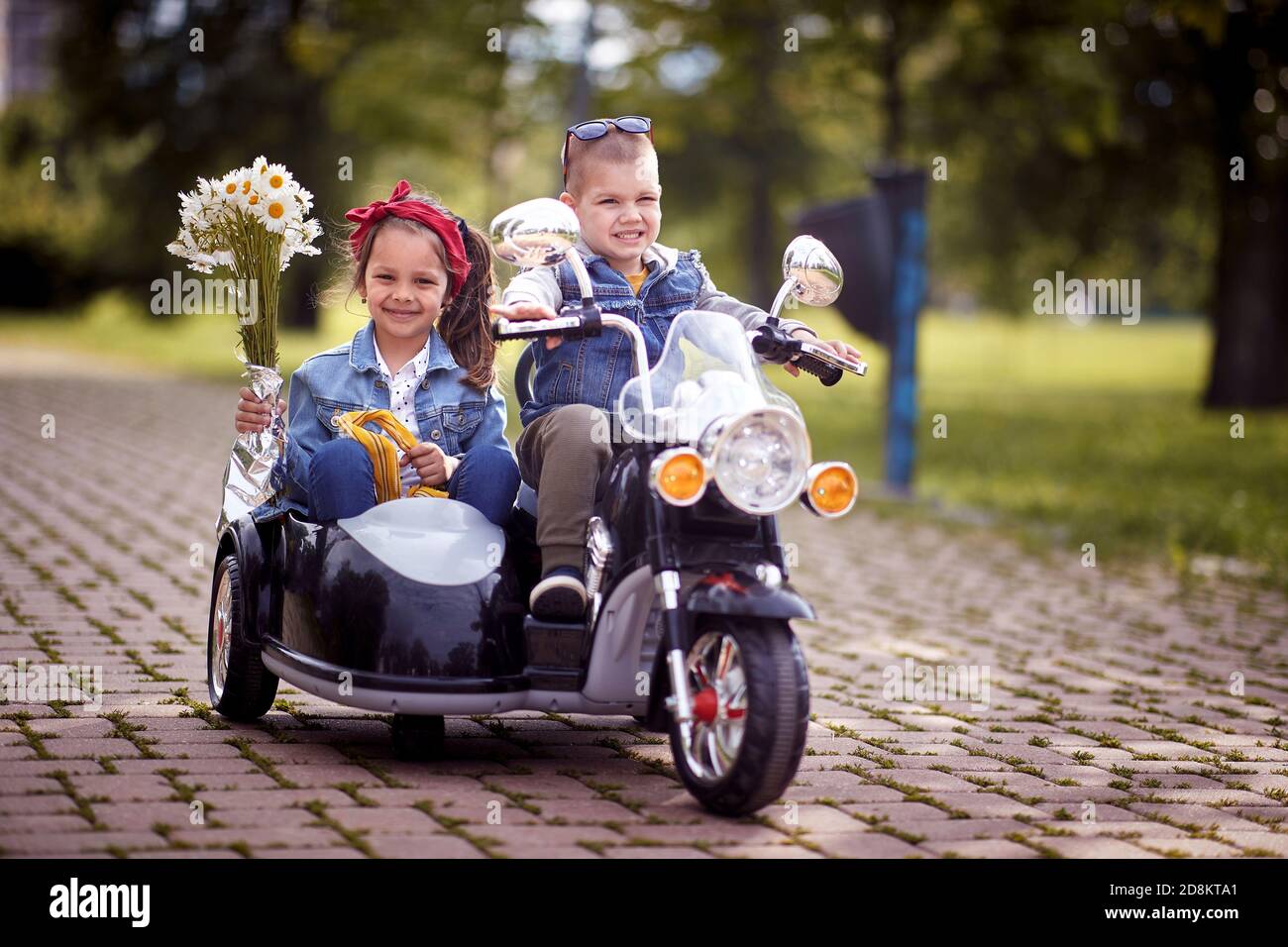 Happy little boy and girl driving in a toy motorcycle in the park Stock ...