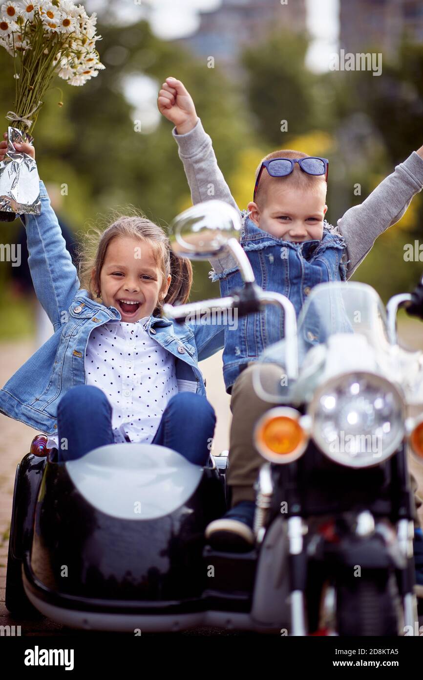 Happy little boy and girl driving in a toy motorcycle in the park Stock ...