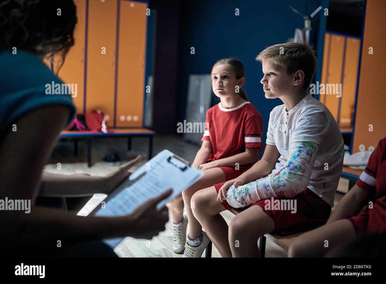Little teammates at the locker room listening to their coach. Children ...
