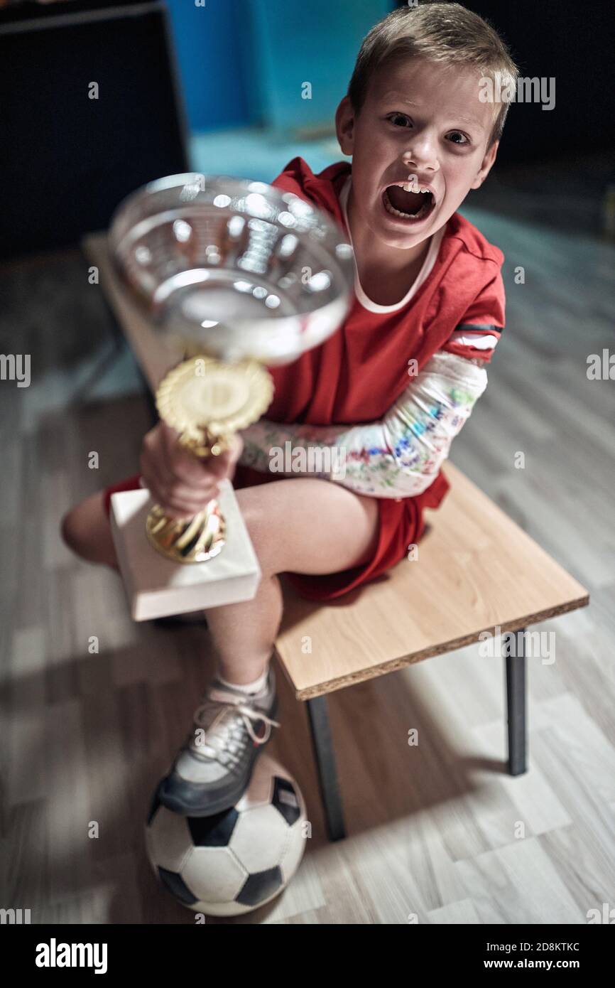 Excited little player at the locker room posing with the trophy won in ...
