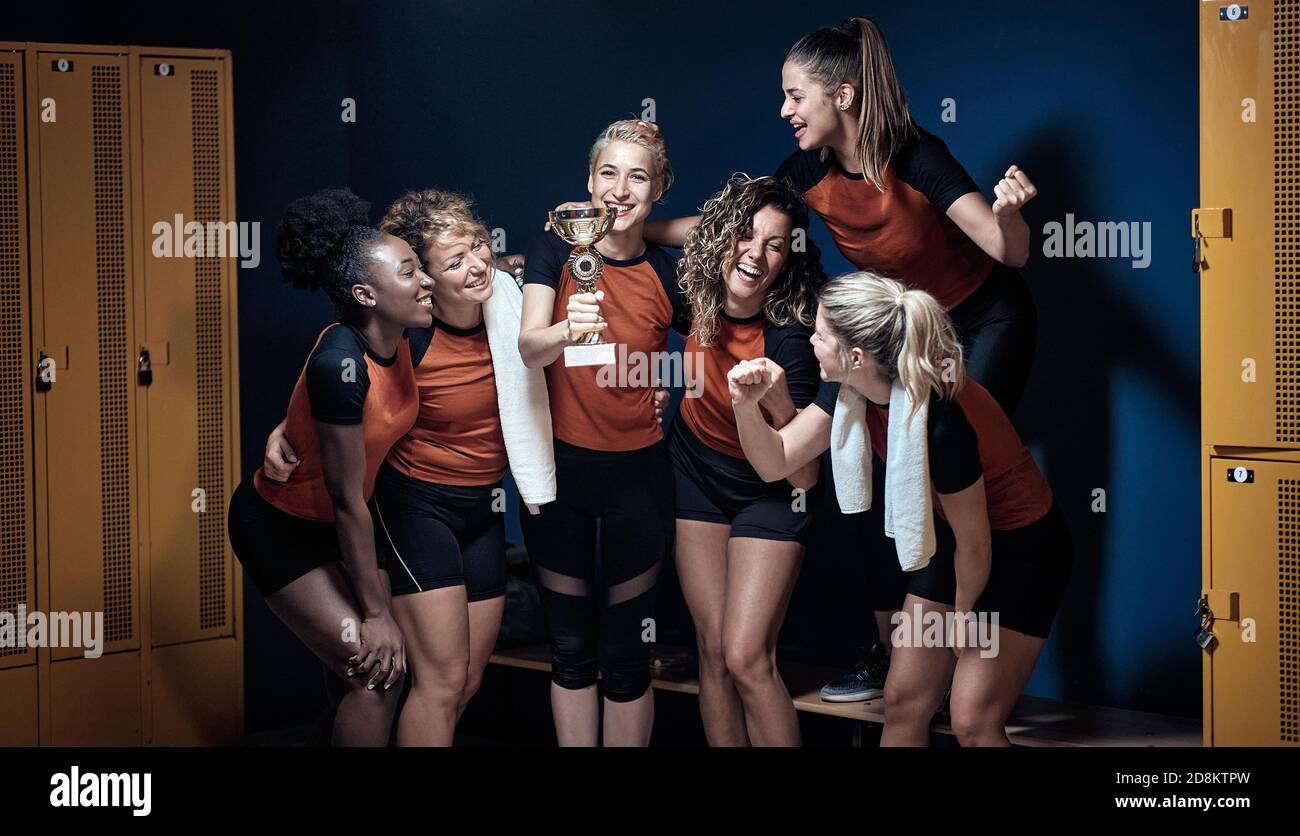 An excited female team at the locker room posing with the trophy after ...