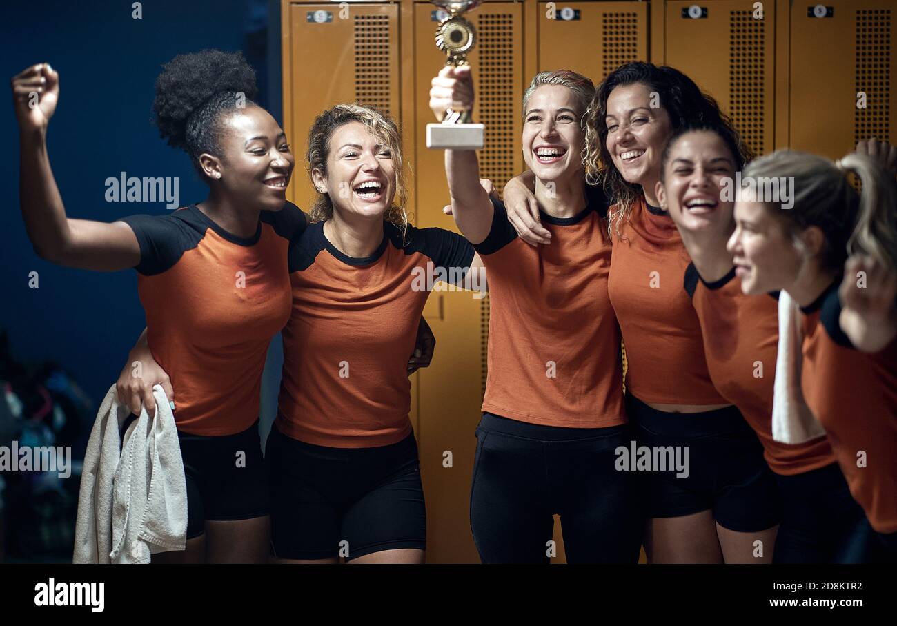 A female team at the locker room posing for a photo with the won trophy ...