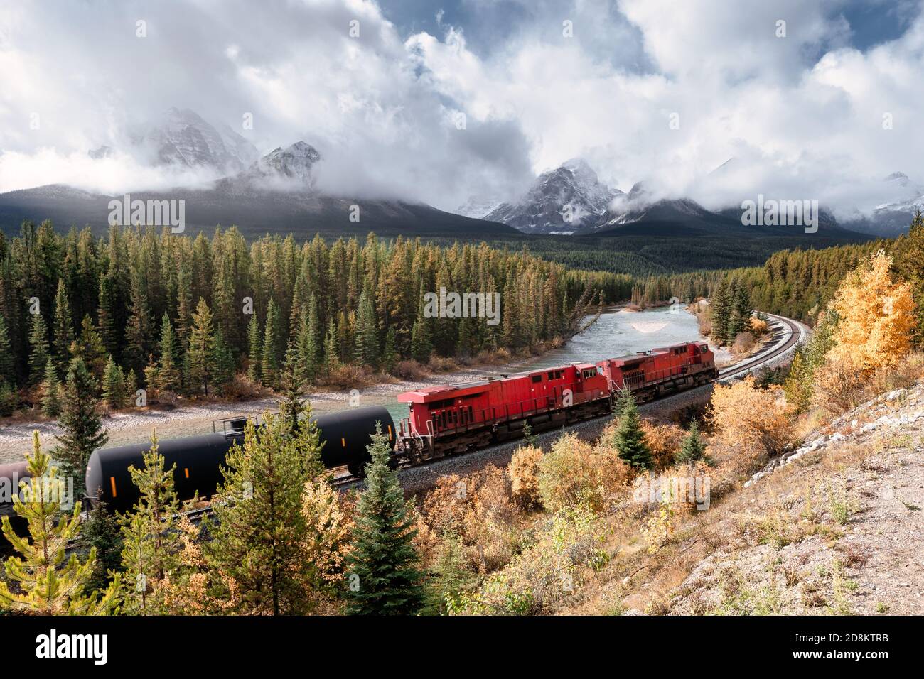 Red long freight train on railway passing through autumn valley with mountain at Morant's Curve ...