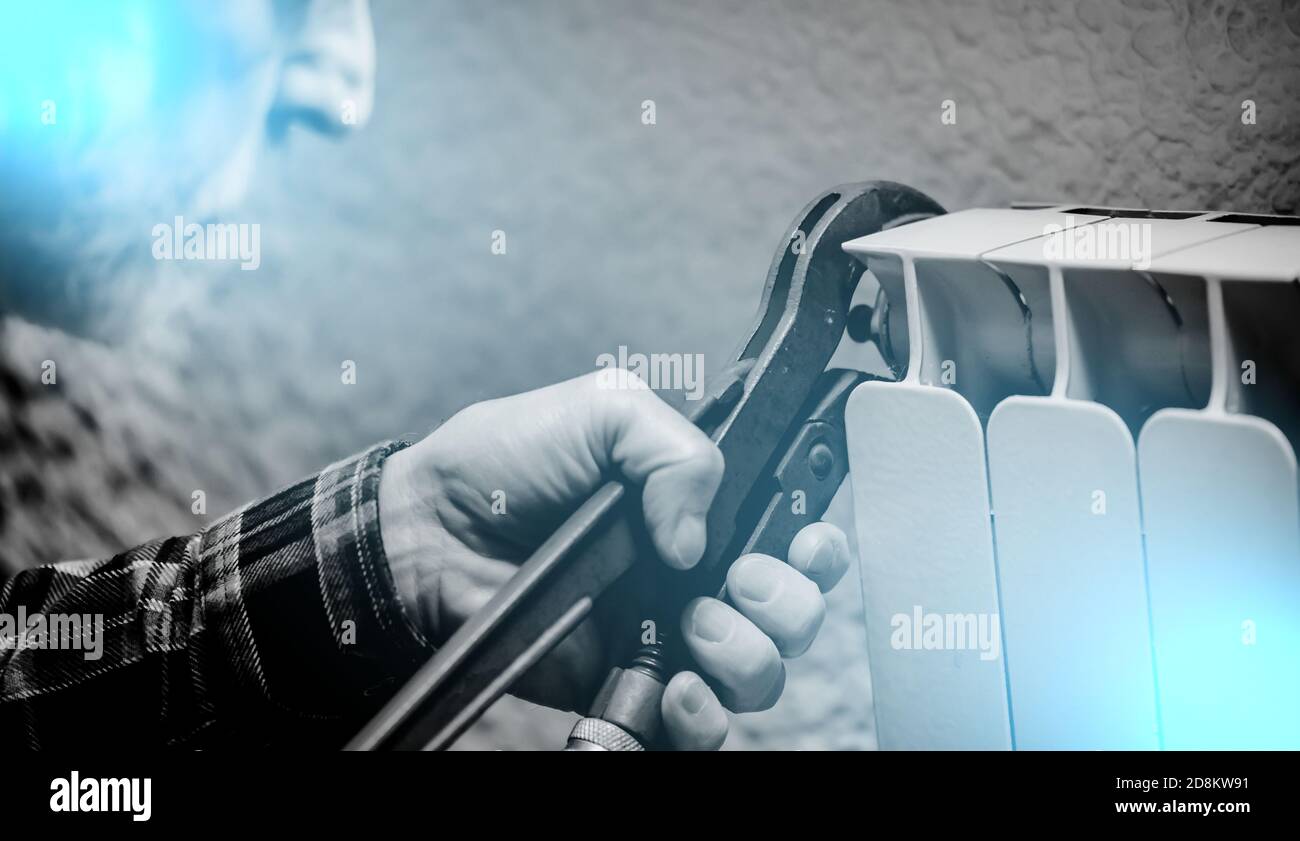 Repairman working on radiator with wrench; light effect Stock Photo - Alamy