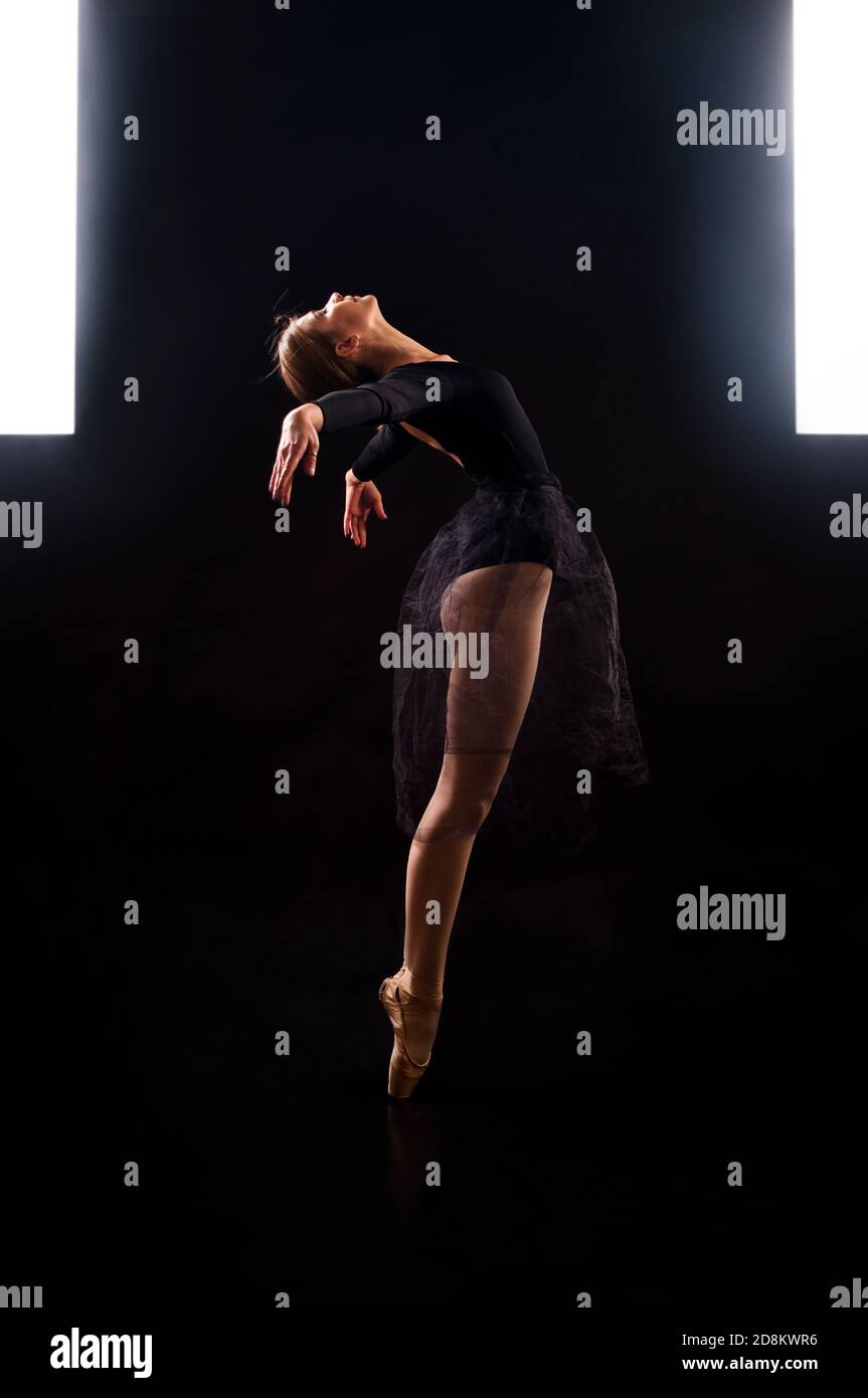 Charming woman ballerina in a black suit, is dancing a ballet in the ...