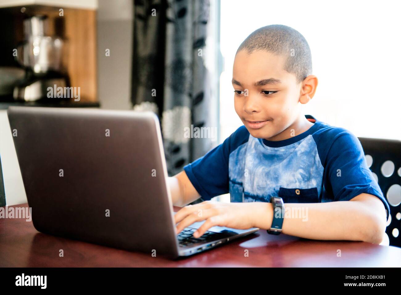Black boy sitting playing on a laptop computer at home Stock Photo - Alamy