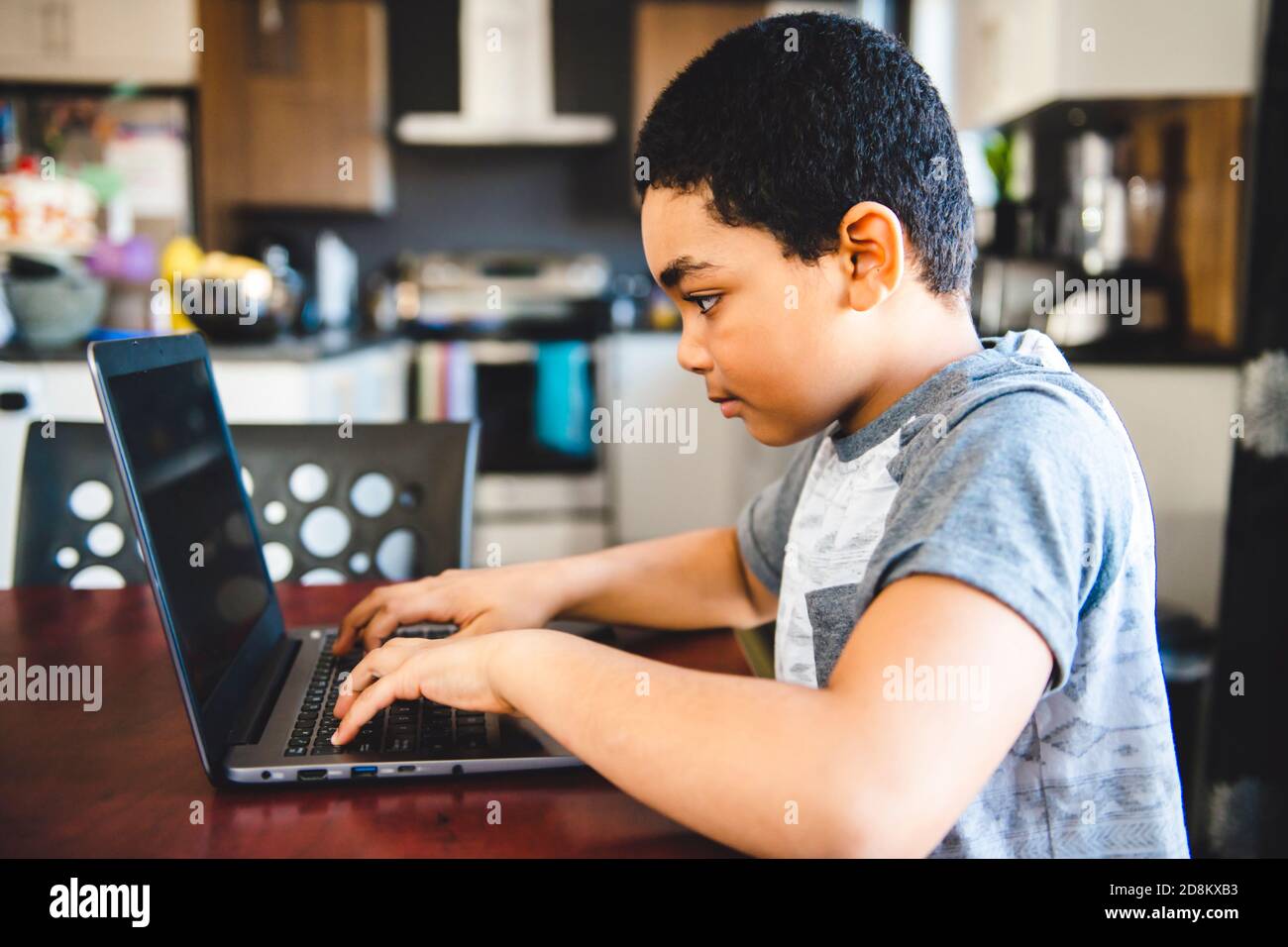 Black boy sitting playing on a laptop computer at home Stock Photo - Alamy