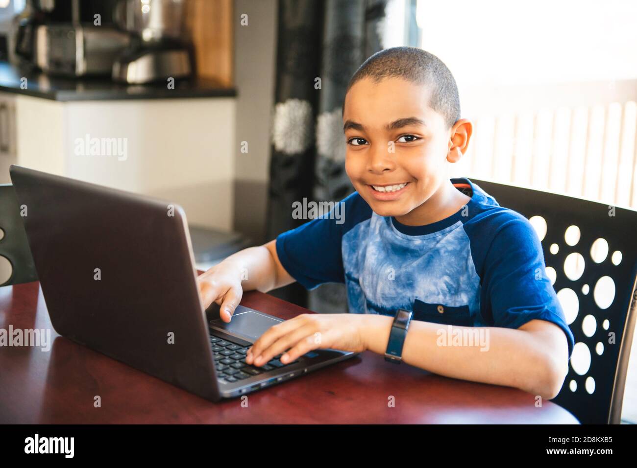 Black boy sitting playing on a laptop computer at home Stock Photo - Alamy
