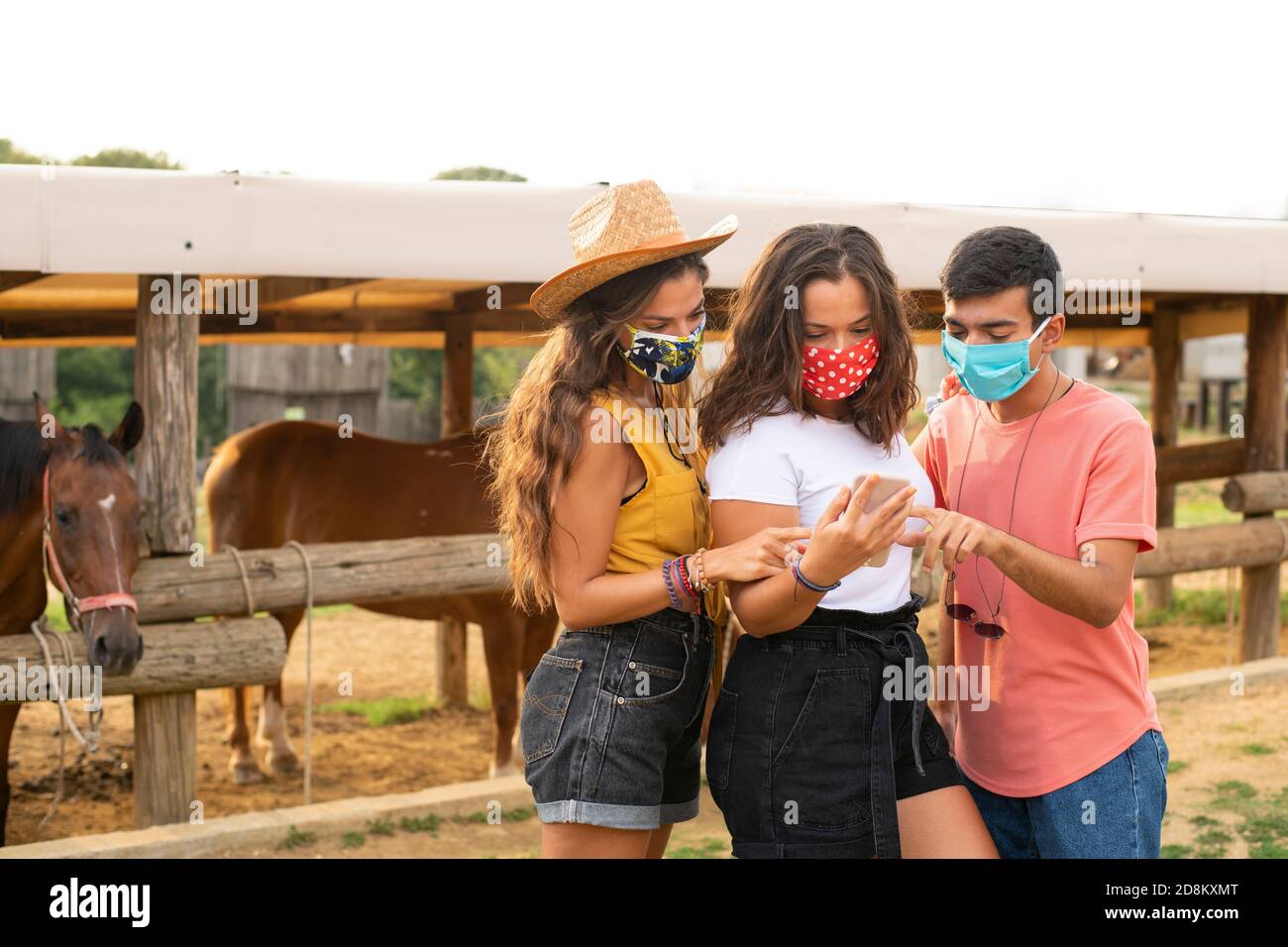 Friends Having Fun Using a Smart Phone in a Ranch with Protective Masks ...