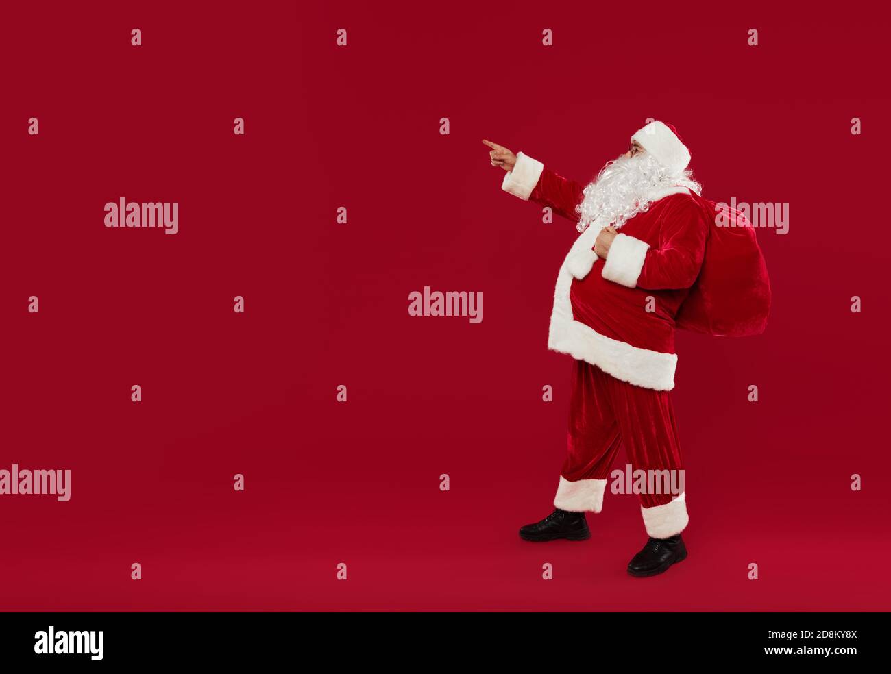 Surprised Santa Claus points to the left side for text. Red studio ...