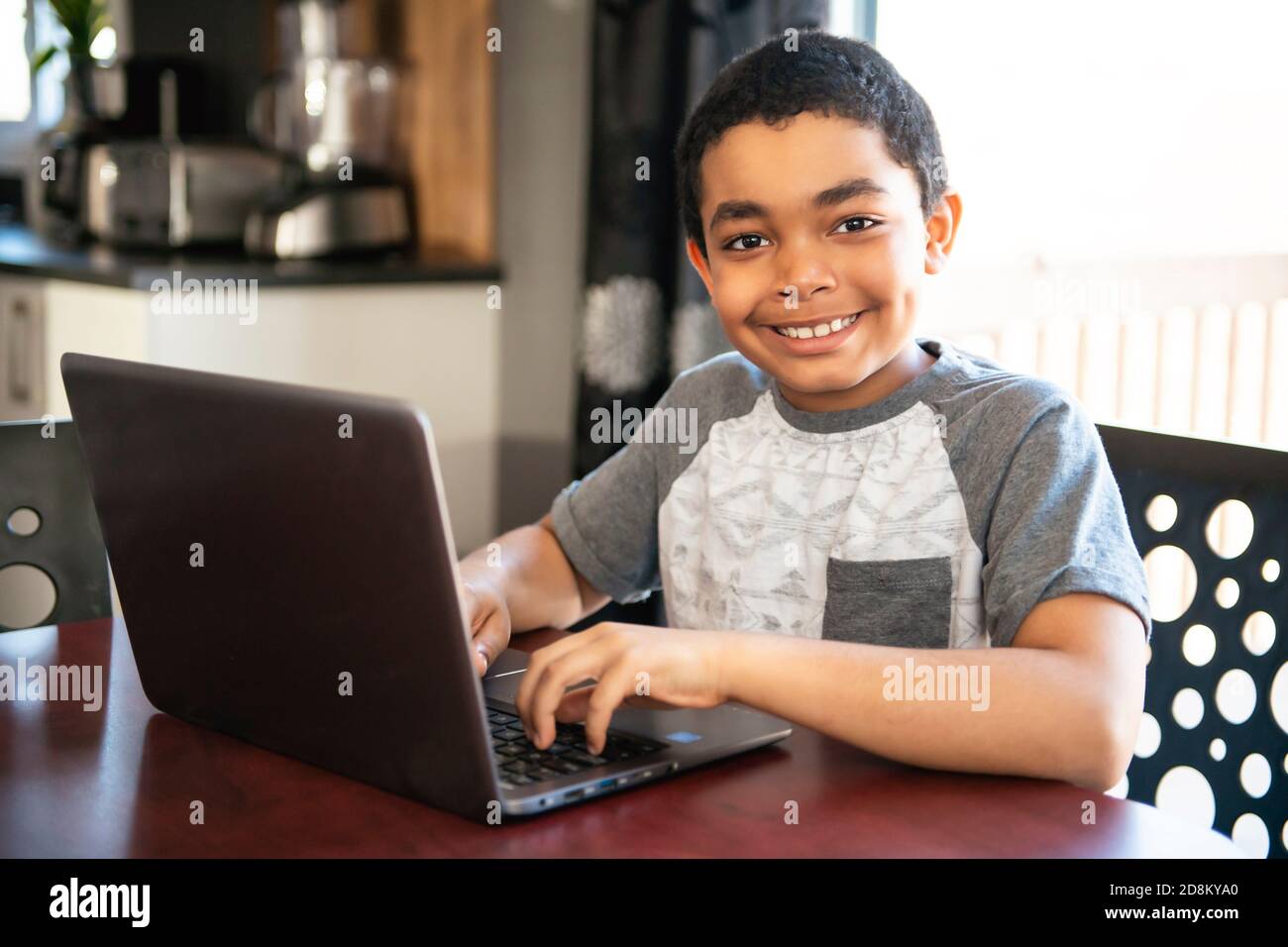 Black boy sitting playing on a laptop computer at home Stock Photo - Alamy