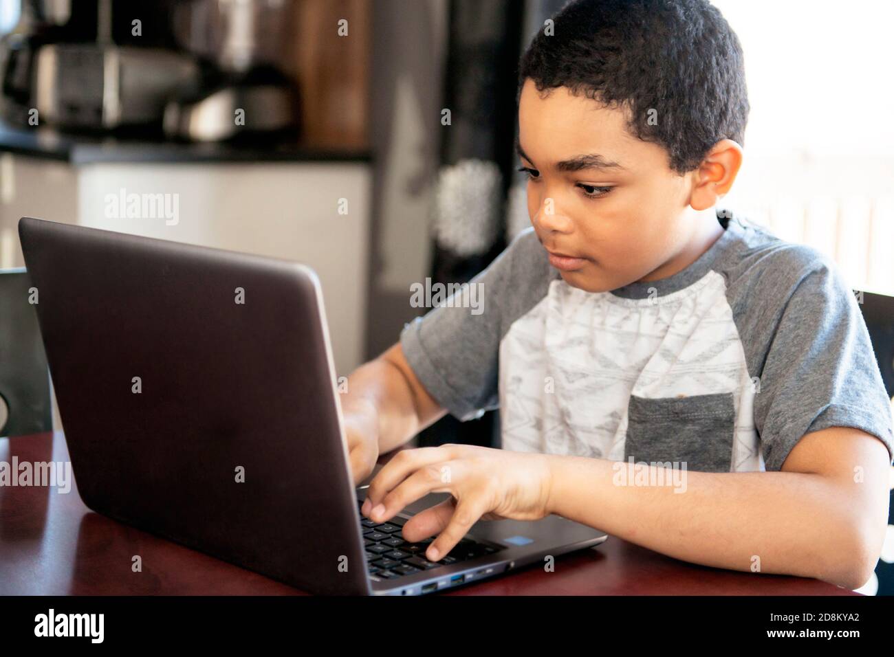 Black boy sitting playing on a laptop computer at home Stock Photo - Alamy