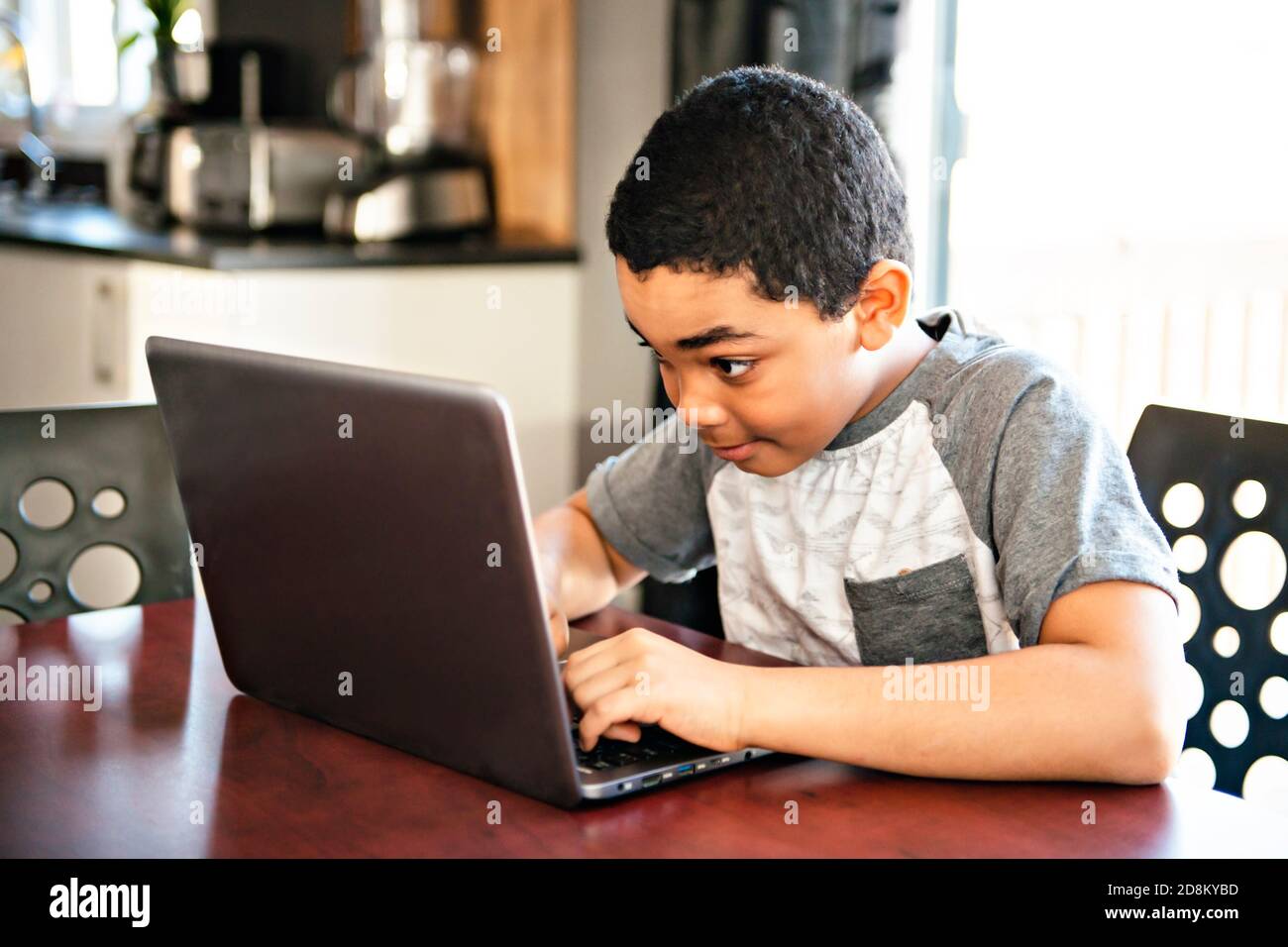 Black boy sitting playing on a laptop computer at home Stock Photo - Alamy